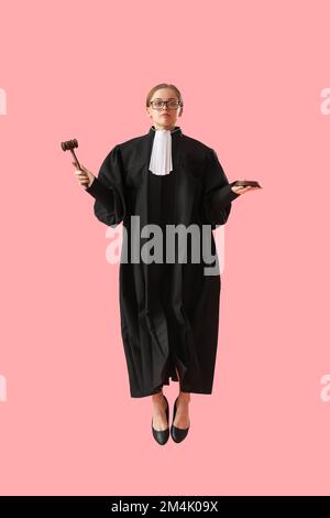 Young female judge with gavel jumping on pink background Stock Photo ...