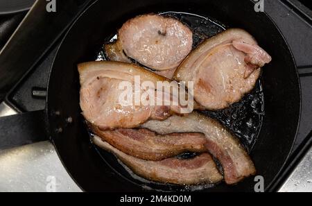 Thick cut bacon slices frying in cast iron pan Stock Photo - Alamy