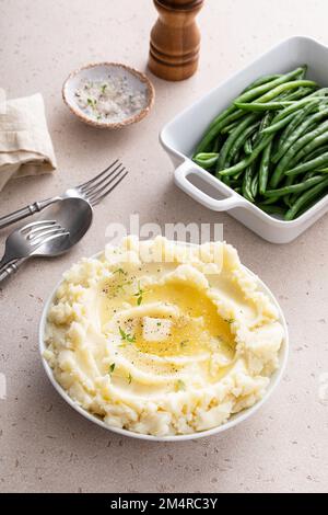 Creamy yellow mashed potatoes in white ceramic bowl garnished with ...