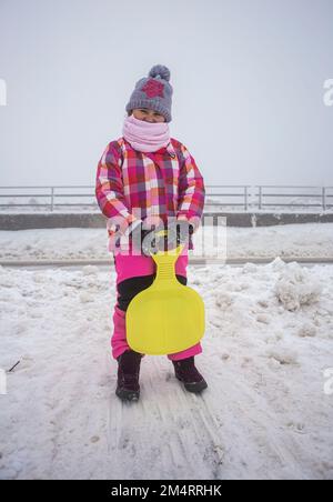 Adorable girl dig snow with shovel and pail on playground covered with ...