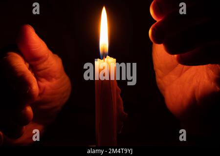 old woman's hands and candle flame in the dark, candle light, mourning ...