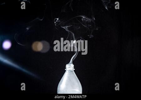 The smoke coming out of a plastic bottle on black background ...