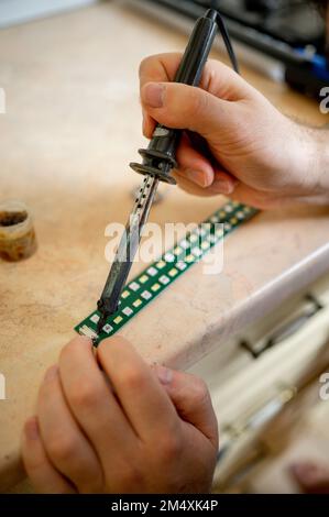 Close-up of a male hands soldering circuit board by soldering iron on ...