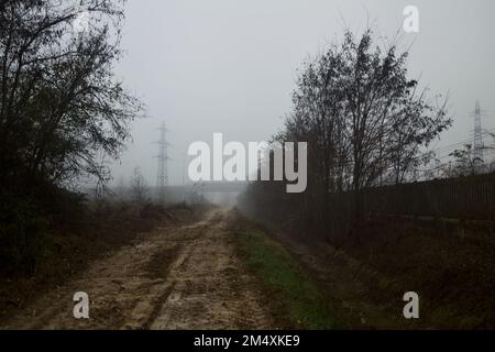 Muddy road next to a railroad track on a foggy day in the italian ...