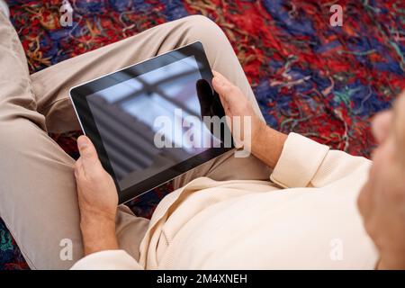 Senior man watching digital tablet while lying on sofa at home Stock ...