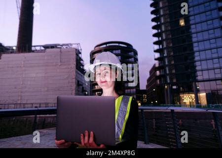 Engineer holding laptop at dusk Stock Photo - Alamy