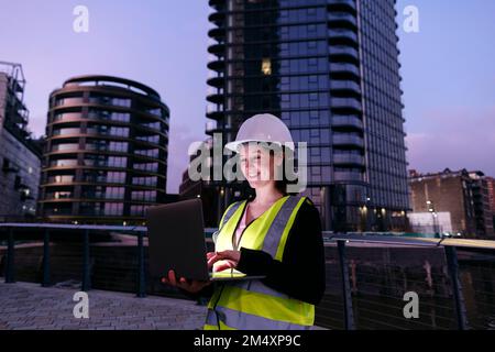 Engineer holding laptop at dusk Stock Photo - Alamy