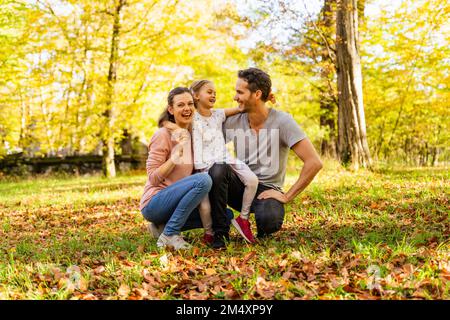Happy parents with daughter in autumn park, family portrait amid fall ...