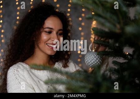 Smiling young beautiful woman decorating Christmas tree Stock Photo - Alamy