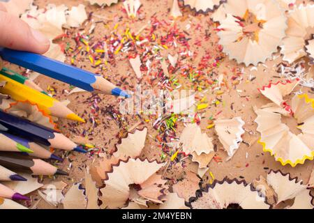 Hand holding Color Pencil over a notebook with pencil shavings Stock ...