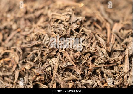 Large-leaved black tea in bulk on the table. Close-up of the surface ...