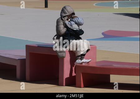 A woman hugs a toddler during cold weather at East Coast Park Precinct ...