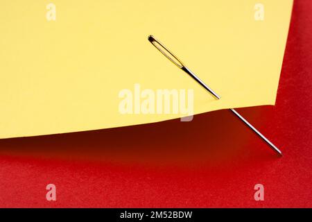 Needle pierced yellow color note paper on red one Stock Photo - Alamy