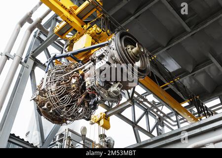 The engine of a gas turbine compressor hangs on a crane during ...