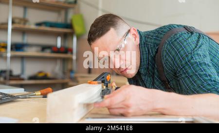 Carpenter measures wooden planks in the workshop Stock Photo - Alamy