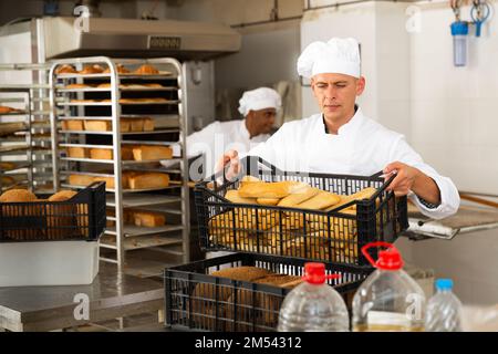 Positive bakery worker lays fresh bread Stock Photo - Alamy