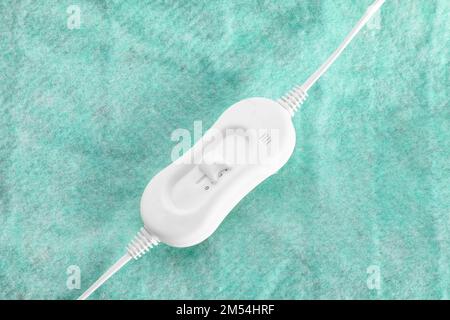 Electric heating pad with controller on bed in dark room, closeup Stock ...