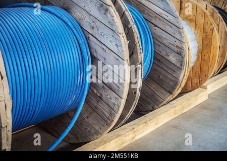 New blue power cable is wound on wooden coil. Background. Cable for ...