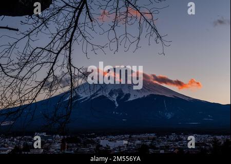 Mount Fuji surrounded by red clouds reflecting the light of the setting ...