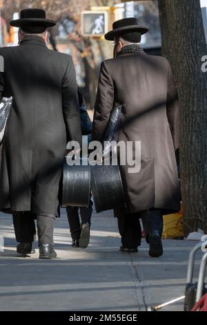 Hasidic Jewish men carry boxes for their younger siblings to be ...