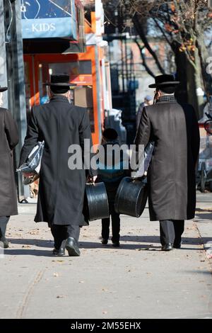 Hasidic Jewish men carry boxes for their younger siblings to be ...
