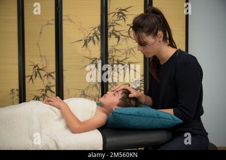 Caucasian woman practicing osteopathy on a child in her office Stock ...