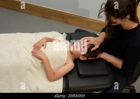Caucasian woman practicing osteopathy on a child in her office Stock ...