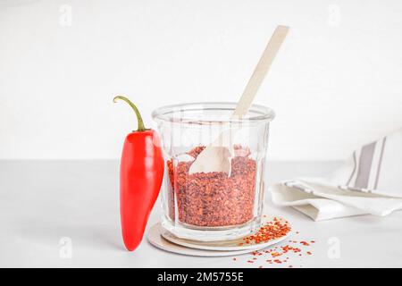 Glass with chipotle chili flakes on light background Stock Photo - Alamy