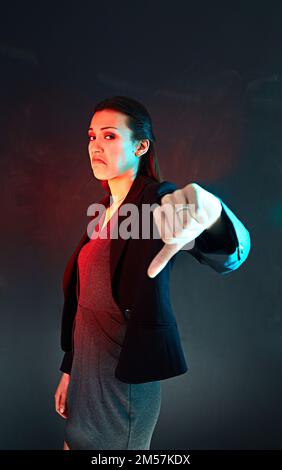 Unimpressed young woman giving a thumbs down gesture Stock Photo - Alamy