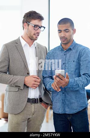 Two young colleagues discussing something in the office Stock Photo - Alamy
