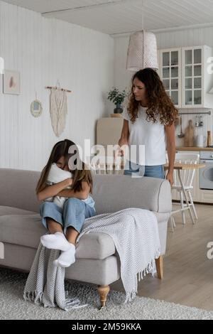 Distressed teenage girl sits on couch at home hugging knees Stock Photo ...
