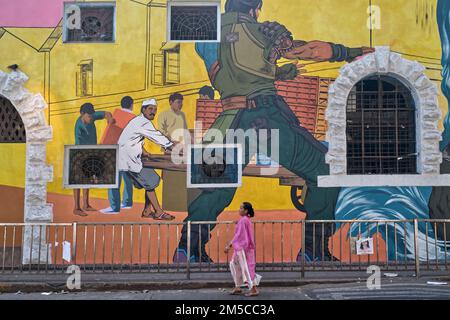 A woman passes a colorful wall painting at Sassoon Docks, Colaba ...