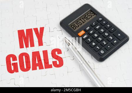 Business concept. On the puzzles lies a calculator and a pen, next to ...