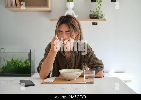 Taiwanese young man eating soup in the living room Stock Photo - Alamy