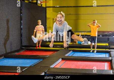 Tween girl doing split in jump in indoor trampoline arena Stock Photo ...