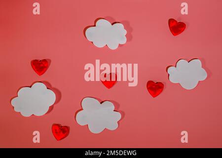 White paper clouds and red textile hearts on a red background ...
