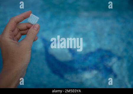 Hand holding small tile from floor of swimming pool. Design of the ...