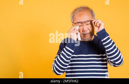 Asian elder man crying raise glasses with tissue wipe red eyes studio ...