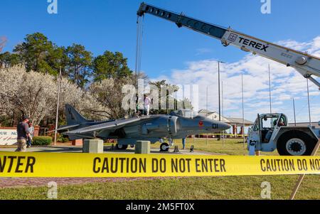 Fleet Readiness Center East employees lower an AV-8B Harrier onto a ...