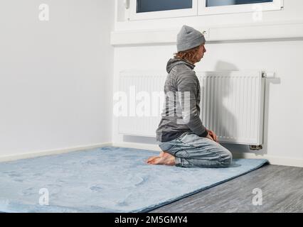 Man freezing in front of heating radiator Stock Photo - Alamy