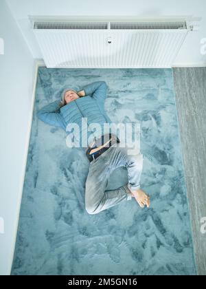 Man lying barefoot in front of heating radiator Stock Photo - Alamy