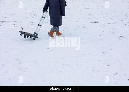 Woman is dragging a cart on the snow Stock Photo - Alamy