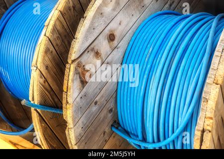 New blue power cable is wound on wooden coil. Background. Cable for ...