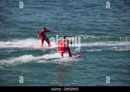 Palestinian surfers dressed in Santa Claus outfits surfing in ...