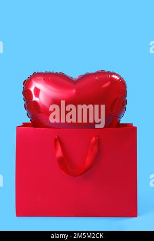 Shopping bag with heart-shaped balloon for Valentine's Day on blue ...