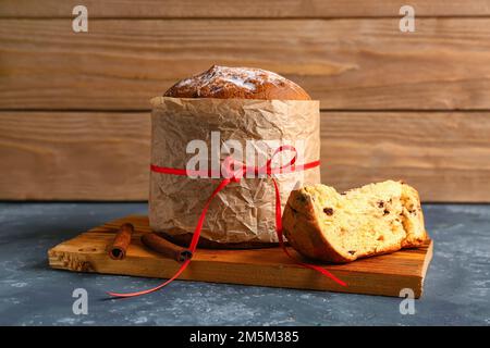 Board with Panettone and cinnamon on table near wooden wall Stock Photo ...
