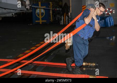 Damage Controlman Fireman Ethan Voss, left, from Abilene, Texas, hands ...