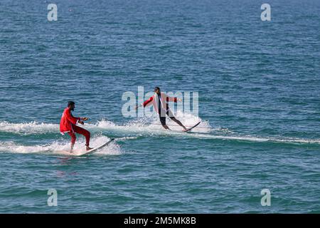 Palestinian surfers dressed in Santa Claus outfits surfing in ...