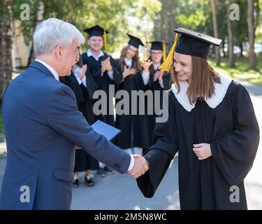 Handshake, diploma and congratulations for student, ceremony and ...