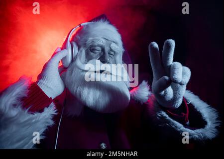 Santa Claus shows 2 fingers listening to music on headphones at a party ...